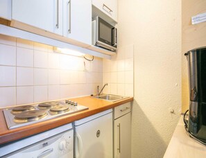Cozinha compacta com fogão, micro-ondas e pia.