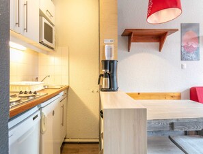 Uma cozinha compacta equipada com micro-ondas, fogão e cafeteira.