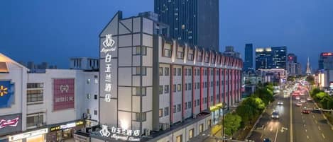 Hotel com fachada moderna, vários andares e sinalização chamativa.