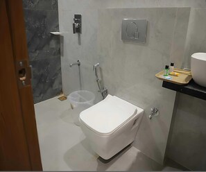 Casa de banho moderna com sanita, chuveiro e lavatório.