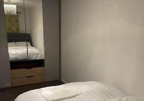 Quarto com cama, guarda-roupa e espelho.
