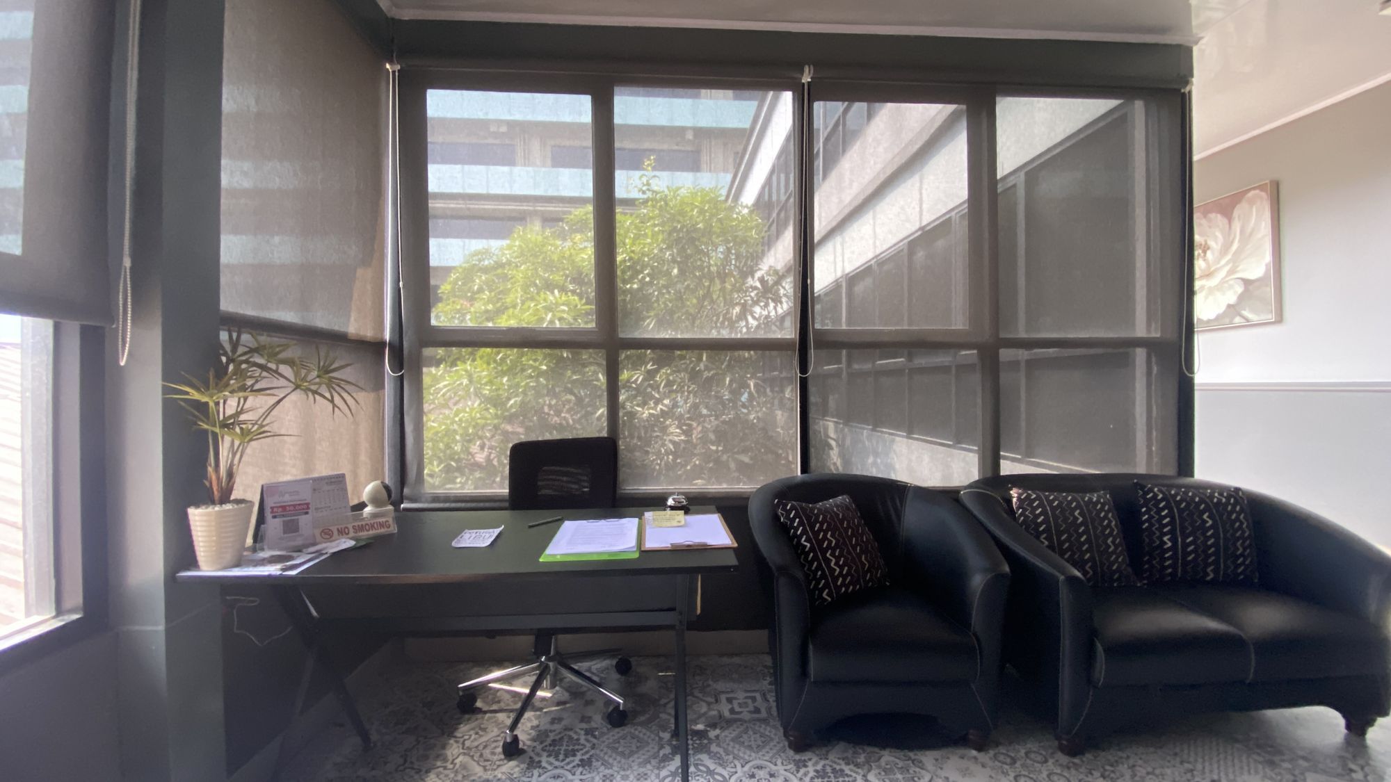 Quarto com escrivaninha, cadeira e amplas janelas.