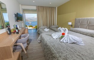 Quarto de hotel com cama, escrivaninha e vista para uma ponte.