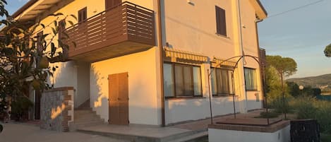 Uma casa de dois andares com varanda, porta da frente e pequeno alpendre.