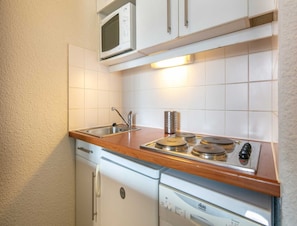 Cozinha compacta com micro-ondas, pia e fogão.