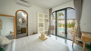 Quarto de hotel com cama, escrivaninha, cadeira, guarda-roupa e vista para uma piscina.