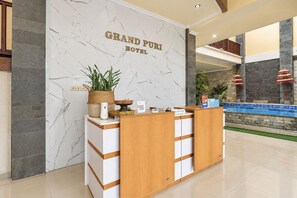 Bancada de recepção de hotel com parede de mármore e área de atendimento.