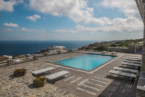 Área da piscina com espreguiçadeiras e vista para o mar.
