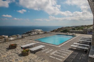 Área da piscina com espreguiçadeiras e vista para o mar.