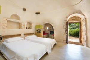 Quarto com duas camas, lareira e um arco que dá para uma área externa.
