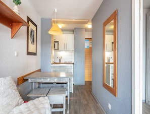 Cozinha compacta com armários brancos, bancada de madeira e luminária pendente amarela.