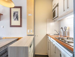 Uma cozinha moderna com bancada de madeira, eletrodomésticos de aço inoxidável e um quadro na parede.