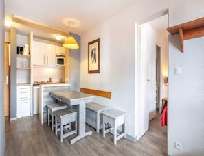 Cozinha compacta com ilha central, armários de madeira e luminária pendente.