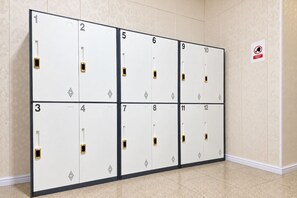 Fileira de armários numerados em um corredor, com uma placa de 'Proibido a entrada' na parede.