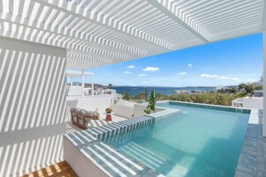 Piscina infinita moderna com vista desobstruída para o oceano.