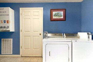 Uma área de lavanderia com porta branca, um quadro na parede e uma máquina de lavar.