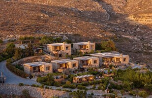 Um conjunto de edifícios de pedra com várias varandas, rodeado por vegetação e um cenário montanhoso.