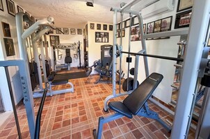 Uma academia com diversos equipamentos de exercícios, um banco e uma parede com quadros.