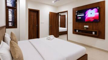 Quarto de hotel com uma cama, televisão na parede e ventilador de teto.