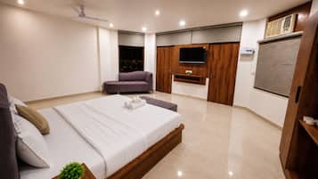 Quarto moderno com uma cama grande, um sofá, uma TV e um ventilador de teto.