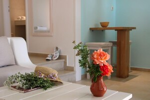 Sala de estar com sofá branco, mesa de centro com um vaso de flores e uma mesa de madeira com uma tigela.