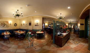 Um restaurante com área de bar, diversas opções de assento incluindo cabines e mesas, e teto decorativo.