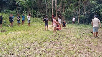 Um grupo de pessoas em ambiente externo, com árvores e grama.