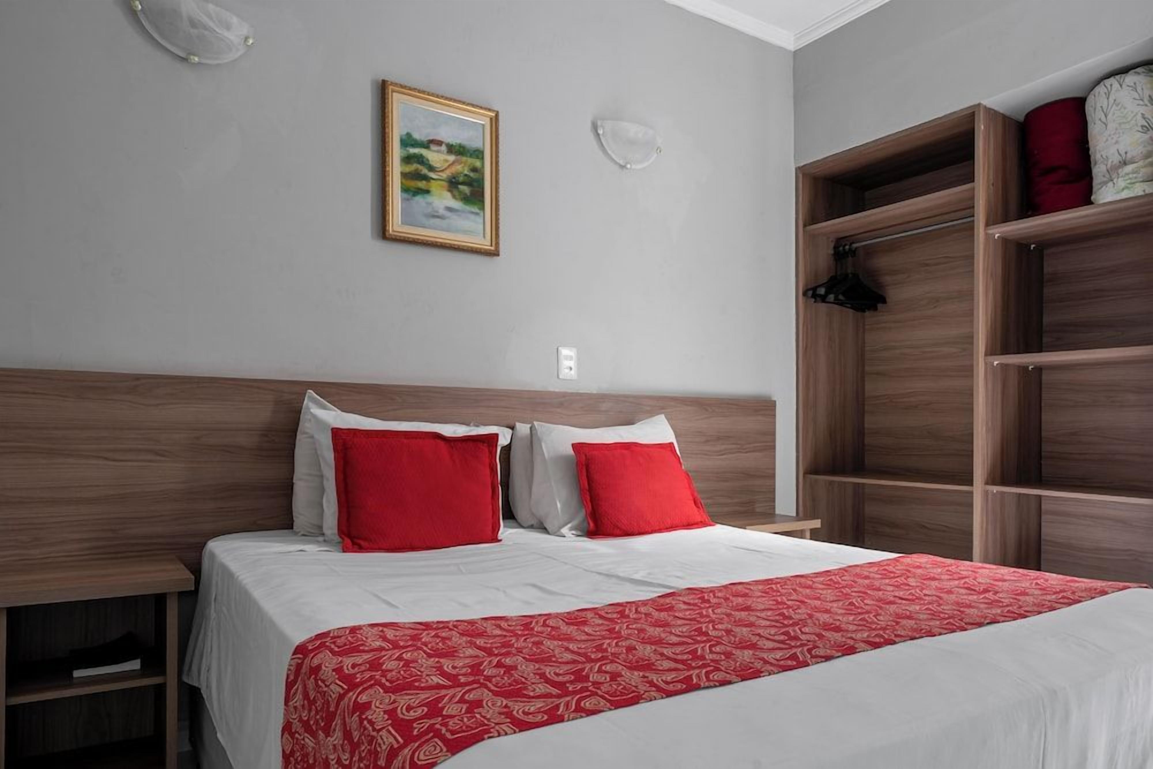 Quarto de hotel com cama, guarda-roupa e um quadro na parede.