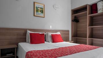 Quarto de hotel com cama, guarda-roupa e um quadro na parede.