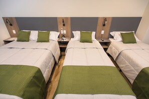 Quarto de hotel com duas camas de solteiro, cada uma com colcha e travesseiro verde, cabeceiras de madeira, mesas de cabeceira com luminárias e um telefone fixado na parede.
