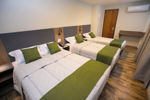 Quarto de hotel com duas camas, piso de madeira, cabeceira de madeira, mesa de cabeceira, telefone e ar condicionado.
