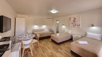 Quarto de hotel com cama, escrivaninha, cadeira e televisão.
