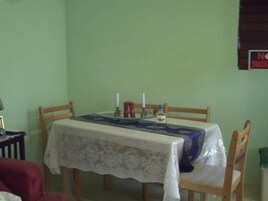 Uma sala de jantar com uma mesa posta para dois, um jogo americano azul e toalha de mesa branca.