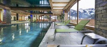 Piscina interna com espreguiçadeiras e vista para as montanhas.