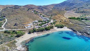 Uma vila costeira com praia, águas azul-claras e campos em socalcos.