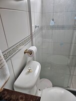 Casa de banho com sanita, chuveiro e barra para toalhas.