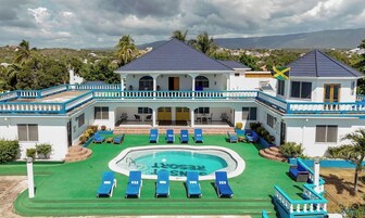 Um resort com piscina, várias espreguiçadeiras e vista para a paisagem ao redor.