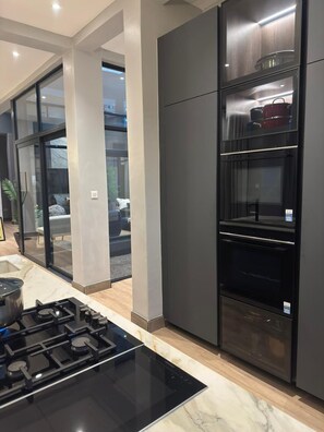 Cozinha moderna com fogão embutido, forno e armários com portas de vidro.