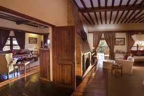 Uma sala de estar ampla com lareira, vigas de madeira e vista através de grandes janelas.