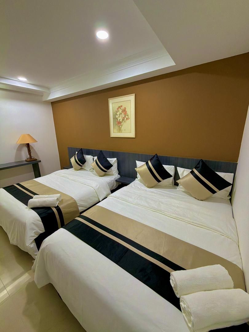 Quarto de hotel com duas camas, uma mesa de cabeceira, um abajur e um quadro na parede.