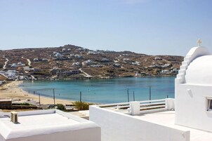 Vista costeira com edifícios brancos, praia e colina com construções.