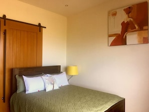 Uma cama com um edredom verde, uma cabeceira de madeira e uma mesa de cabeceira com abajur.