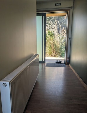 Corredor com radiador, porta para o exterior e tapete na entrada.