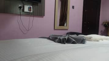 Quarto de hotel com cama, televisão de tela plana na parede, espelho e porta.