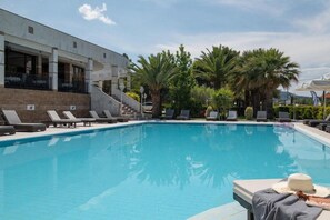 Piscina com espreguiçadeiras e palmeiras.