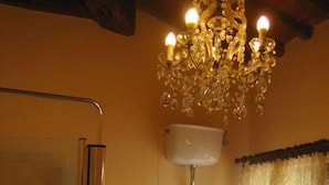 Casa de banho com chuveiro, sanita, bidé e um candelabro.
