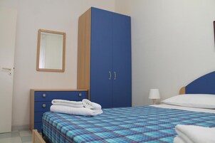Quarto com cama, guarda-roupa, espelho e mesa de cabeceira.