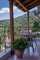 Varanda com mesa, planta em vaso e vista panorâmica das montanhas.