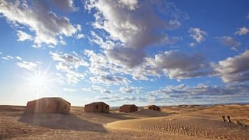 Paisagem desértica com três edifícios pequenos e isolados.