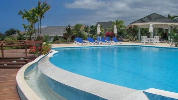Piscina com espreguiçadeiras e um gazebo.